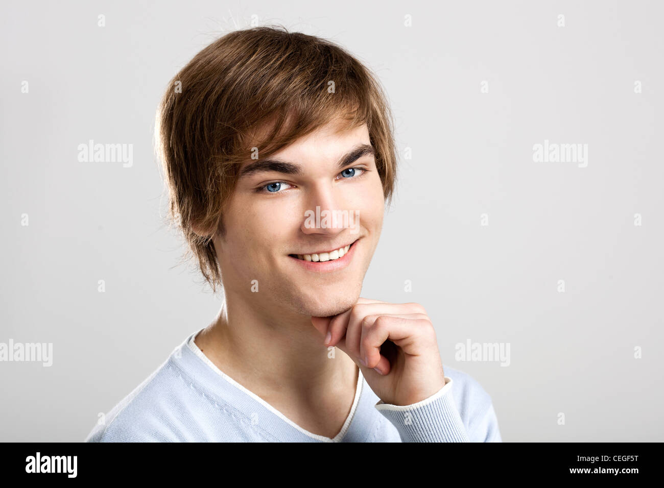 Portrait of a handsome and happy young man thinking, over a gray ...
