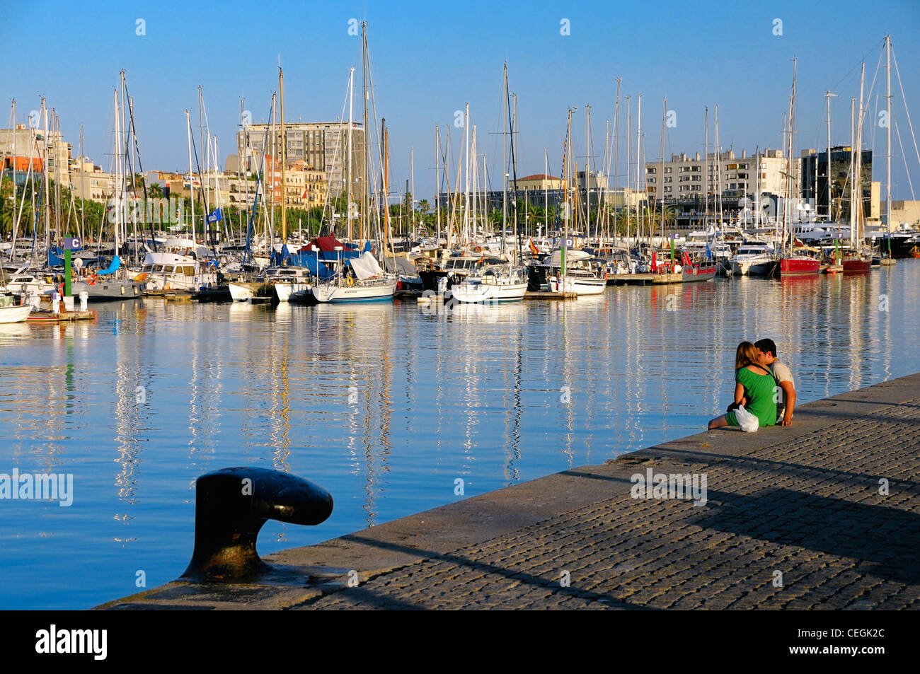 A couple enjoys the sunset at the marina in Port Vell, Barcelona, Spain ...