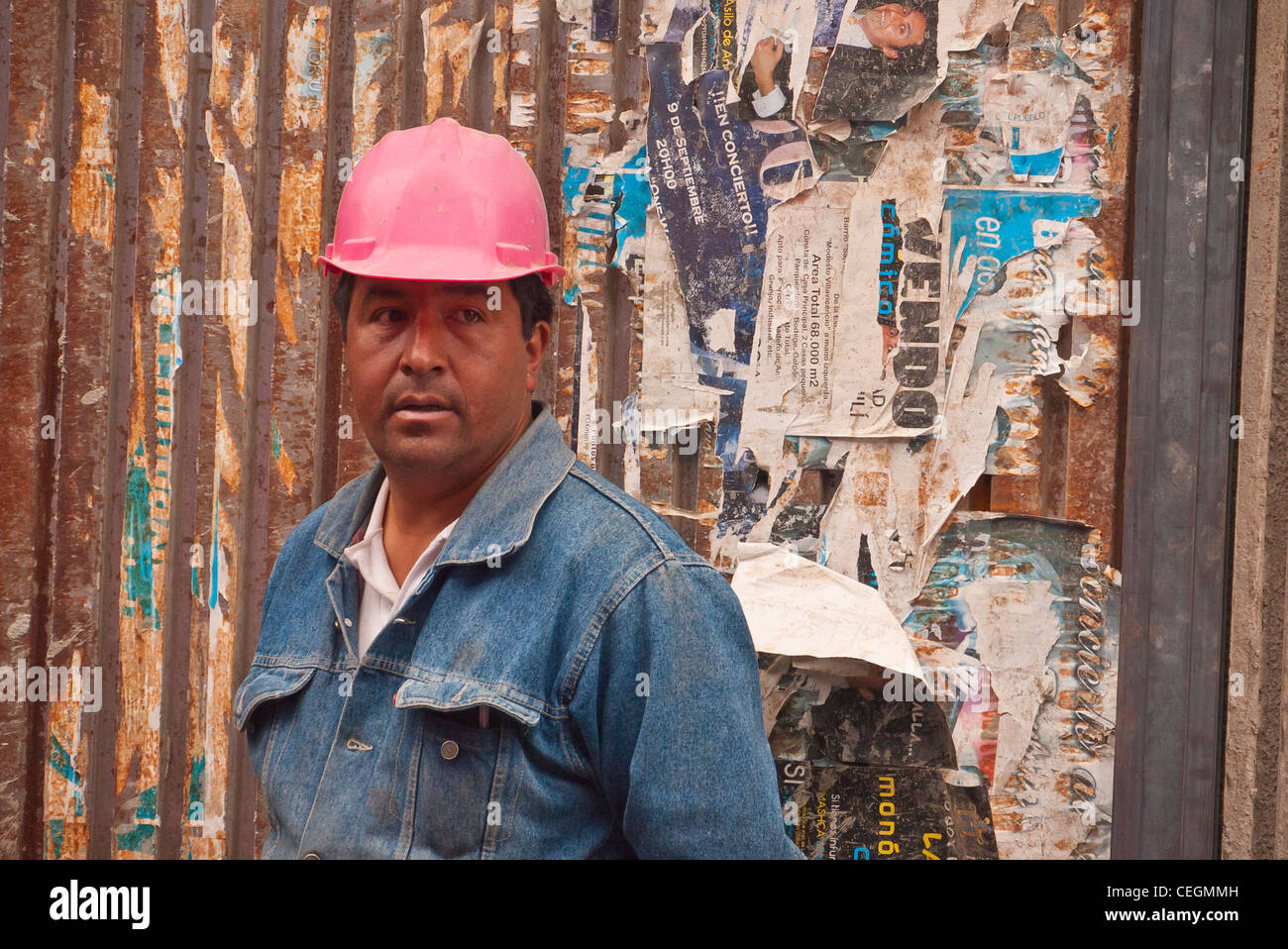 A Hispanic construction worker in a pink hardhat stands in front of a ...