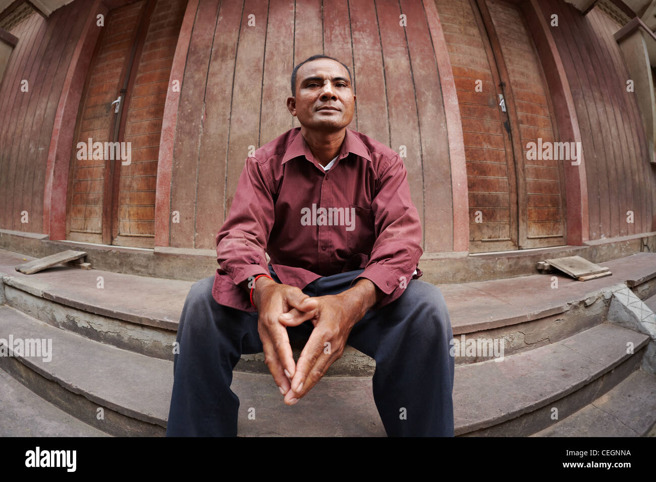 Portrait of mid adult poor asian man with hands joined, looking at ...