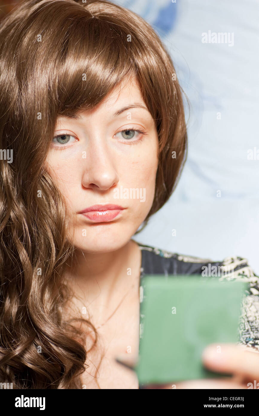 Woman looking at hair in mirror Stock Photo - Alamy