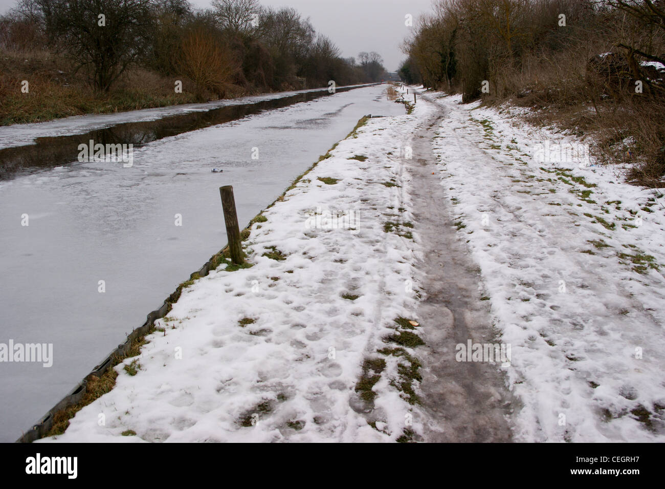 Frozen Slough arm of the Grand Union canal and towpath with snow near ...