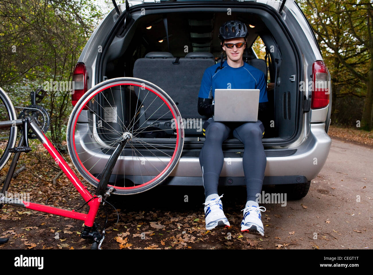 Cyclist using laptop from boot of car Stock Photo - Alamy