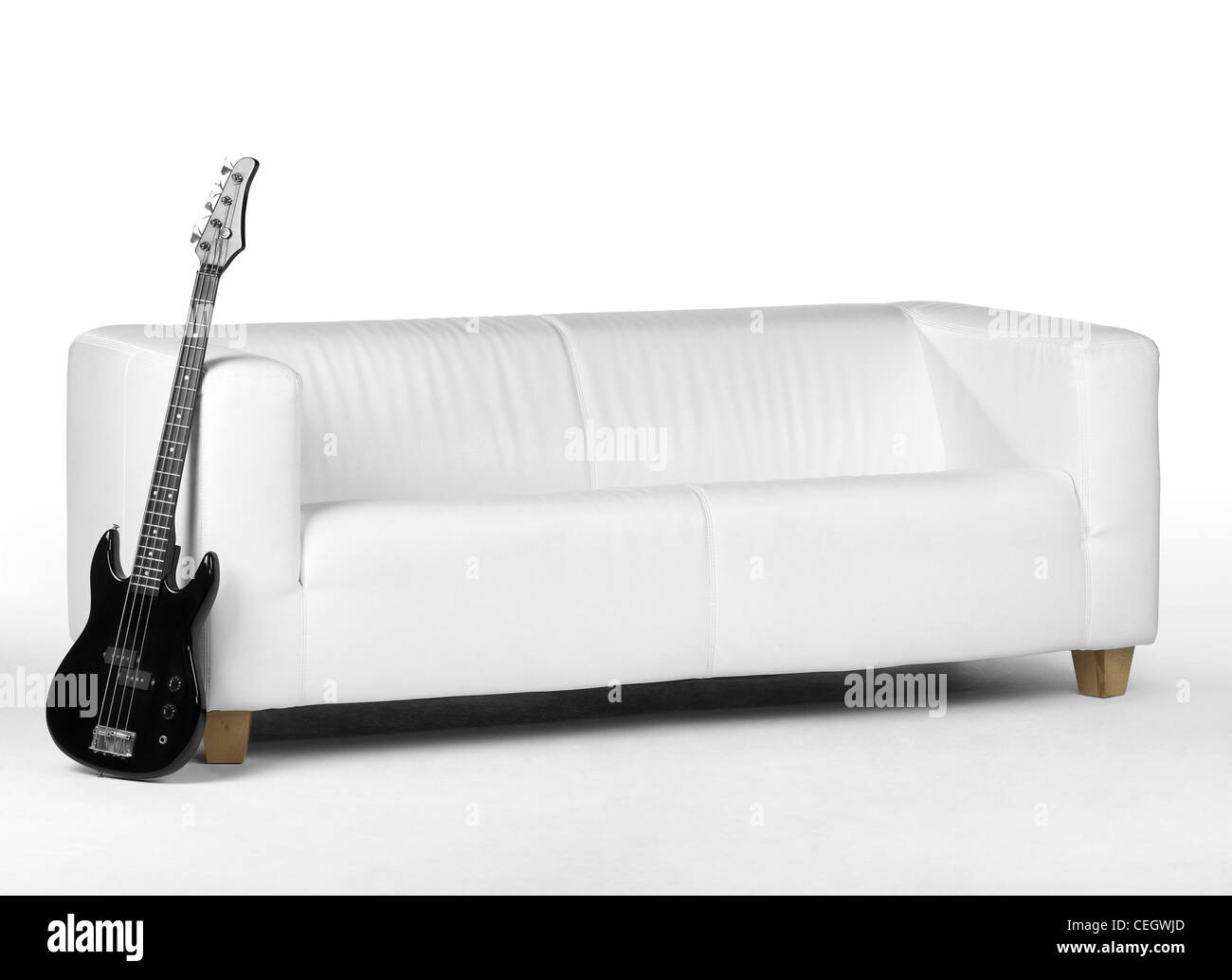 black bass guitar lean against white couch in white back Stock Photo ...