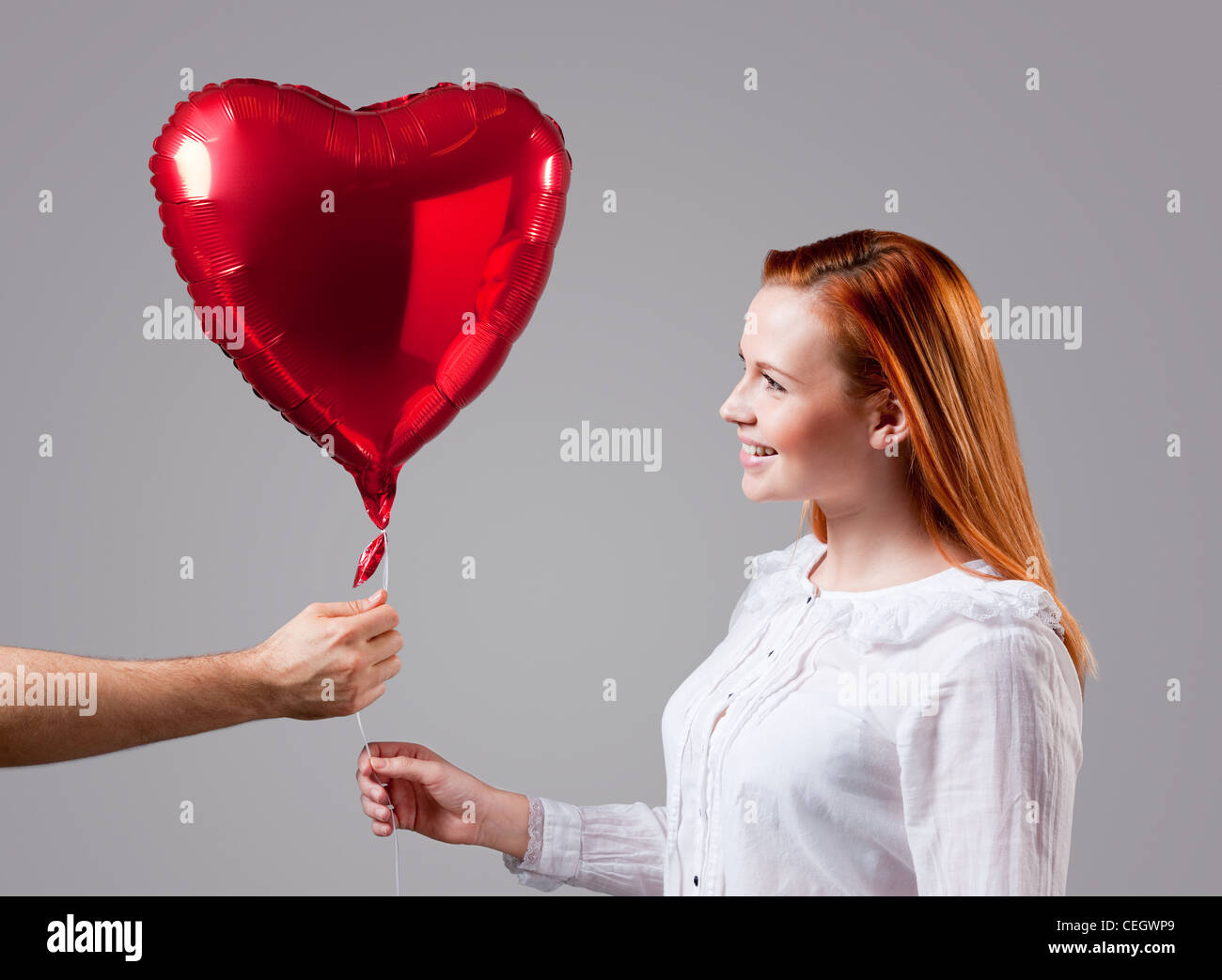Young woman being given heart shaped balloon Stock Photo - Alamy