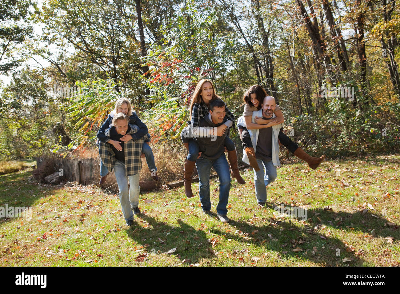 Couples having a piggyback race outdoors Stock Photo - Alamy
