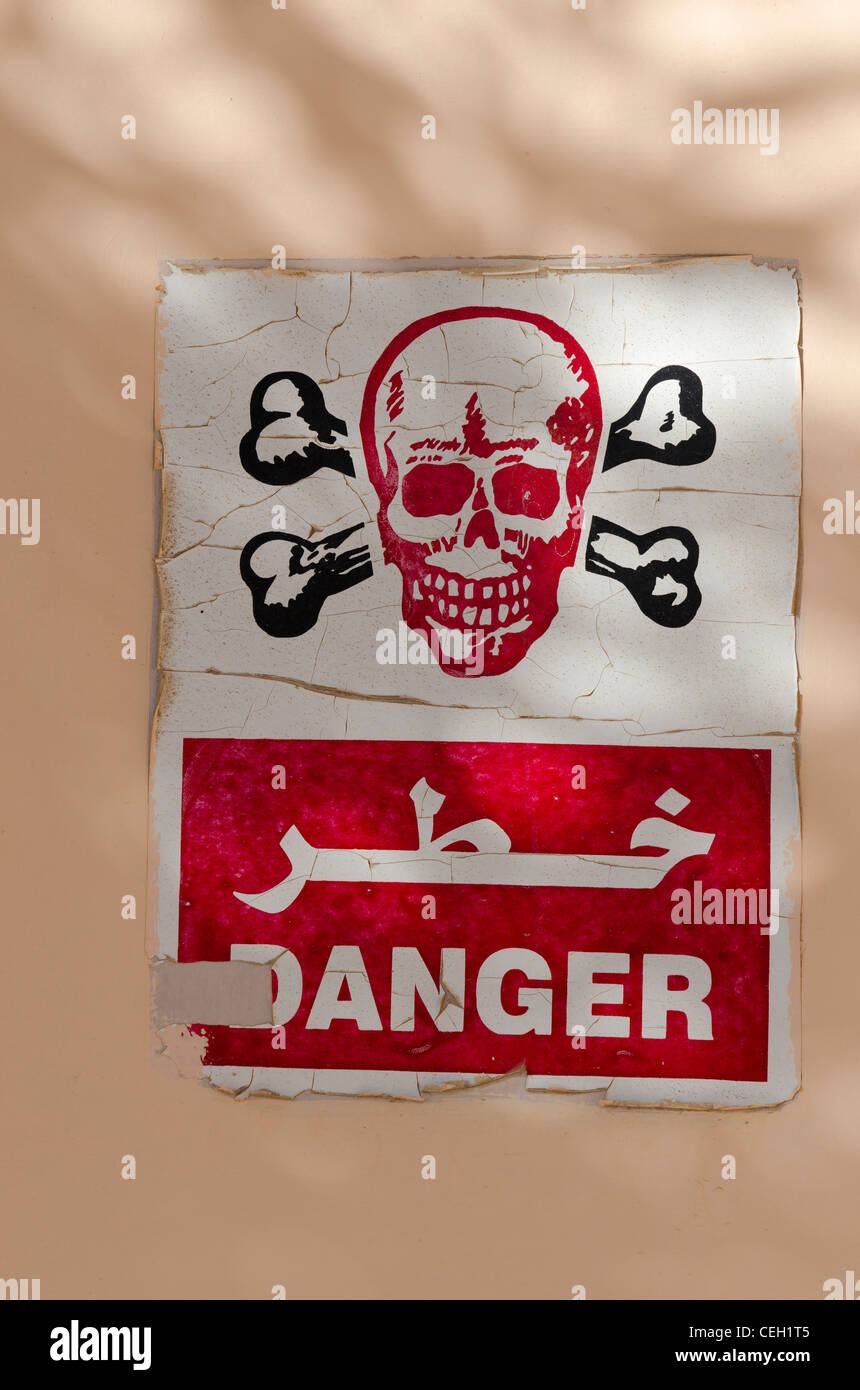 Sign Danger in English and Arabic - peeling paint Stock Photo - Alamy