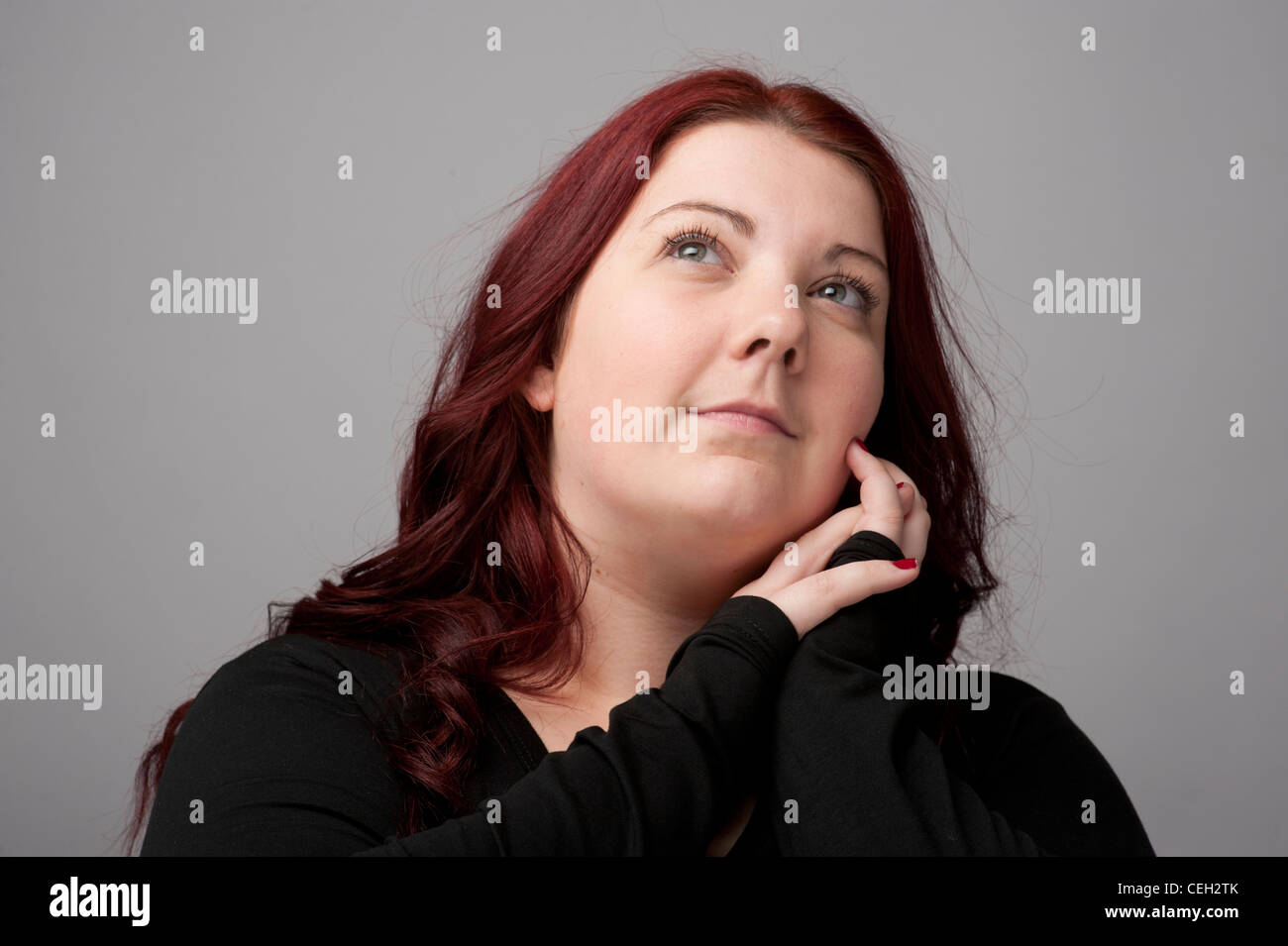 A auburn haired caucasian woman thinking pondering thoughtful looking ...