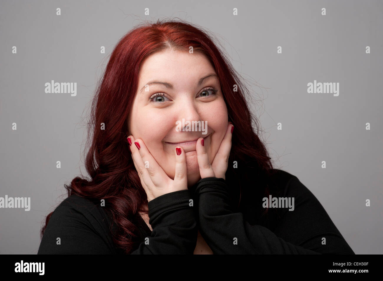 A chubby round faced auburn haired caucasian woman looking happy ...