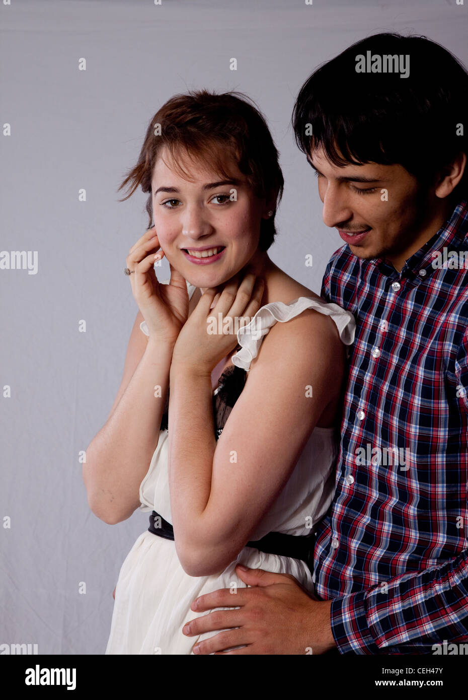 Cute white couple snuggling together, the man has his hands on her hips ...