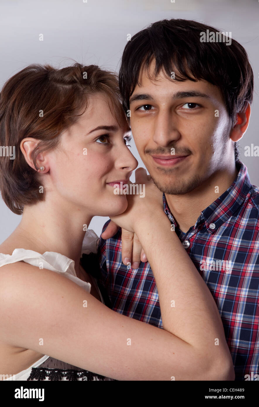 Cute white couple snuggling together, the man has his arm around her ...