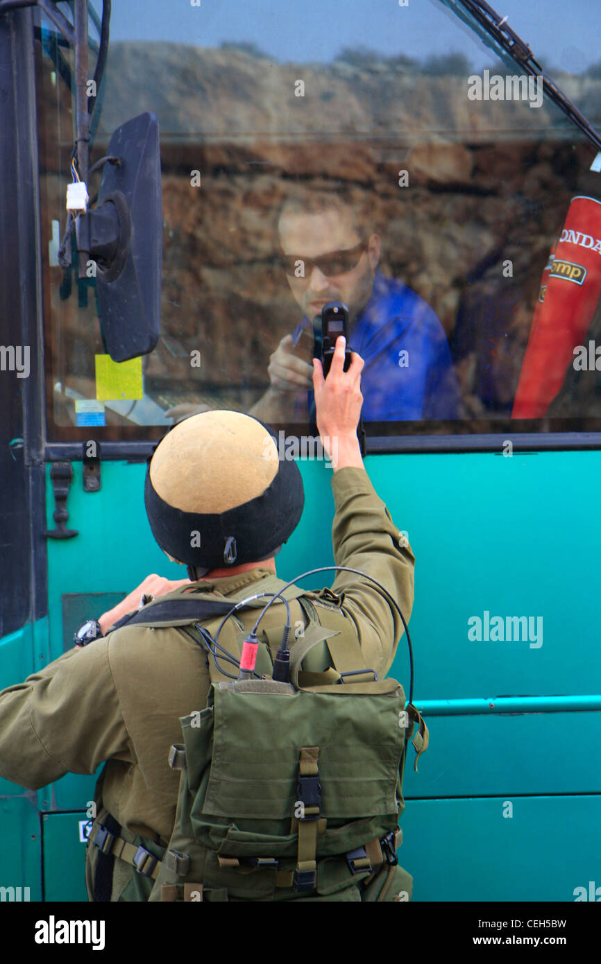 An Israeli soldier uses a cell phone to communicate through a window ...