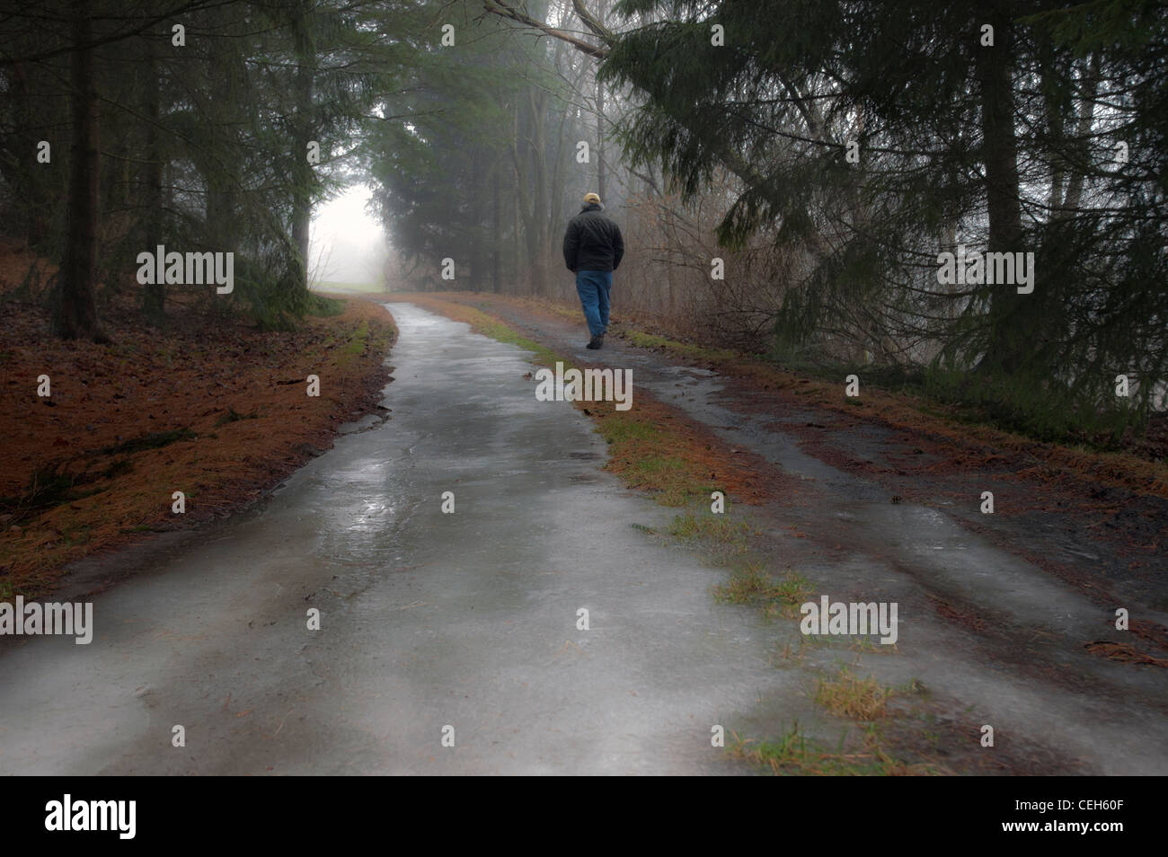 one man walking alone on an icy road Stock Photo - Alamy