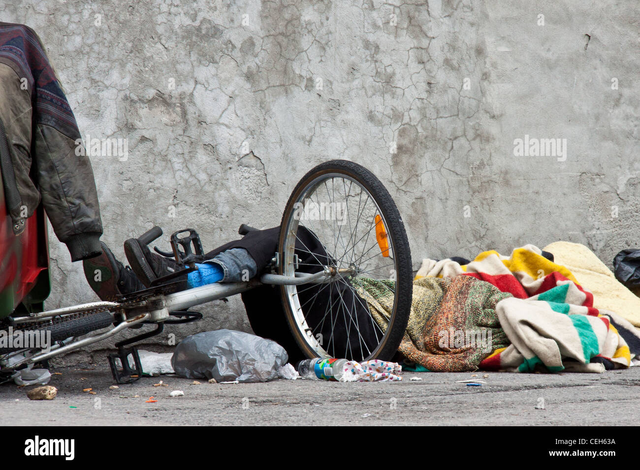 Homeless sleeping on the sidewalk guarding his bicycle with foots in ...