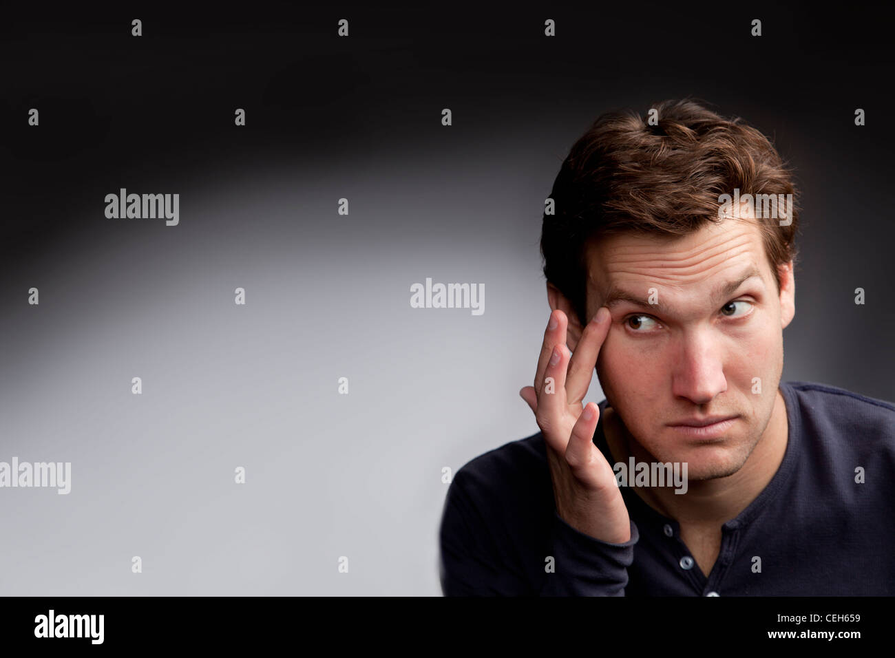 Man with hand by temple in deep thought Stock Photo - Alamy