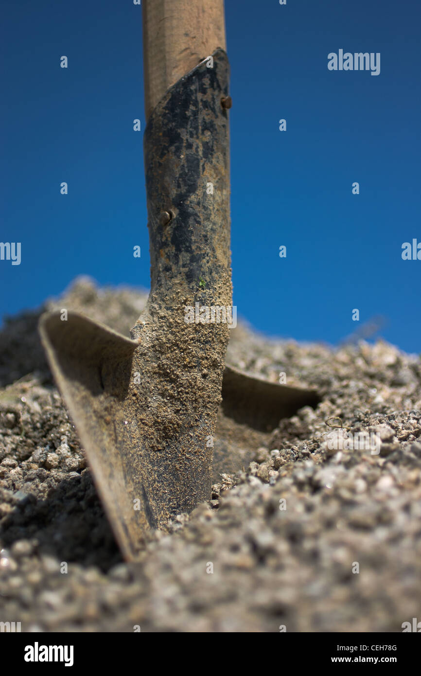 Shovel in the sand with blue sky in the background Stock Photo - Alamy