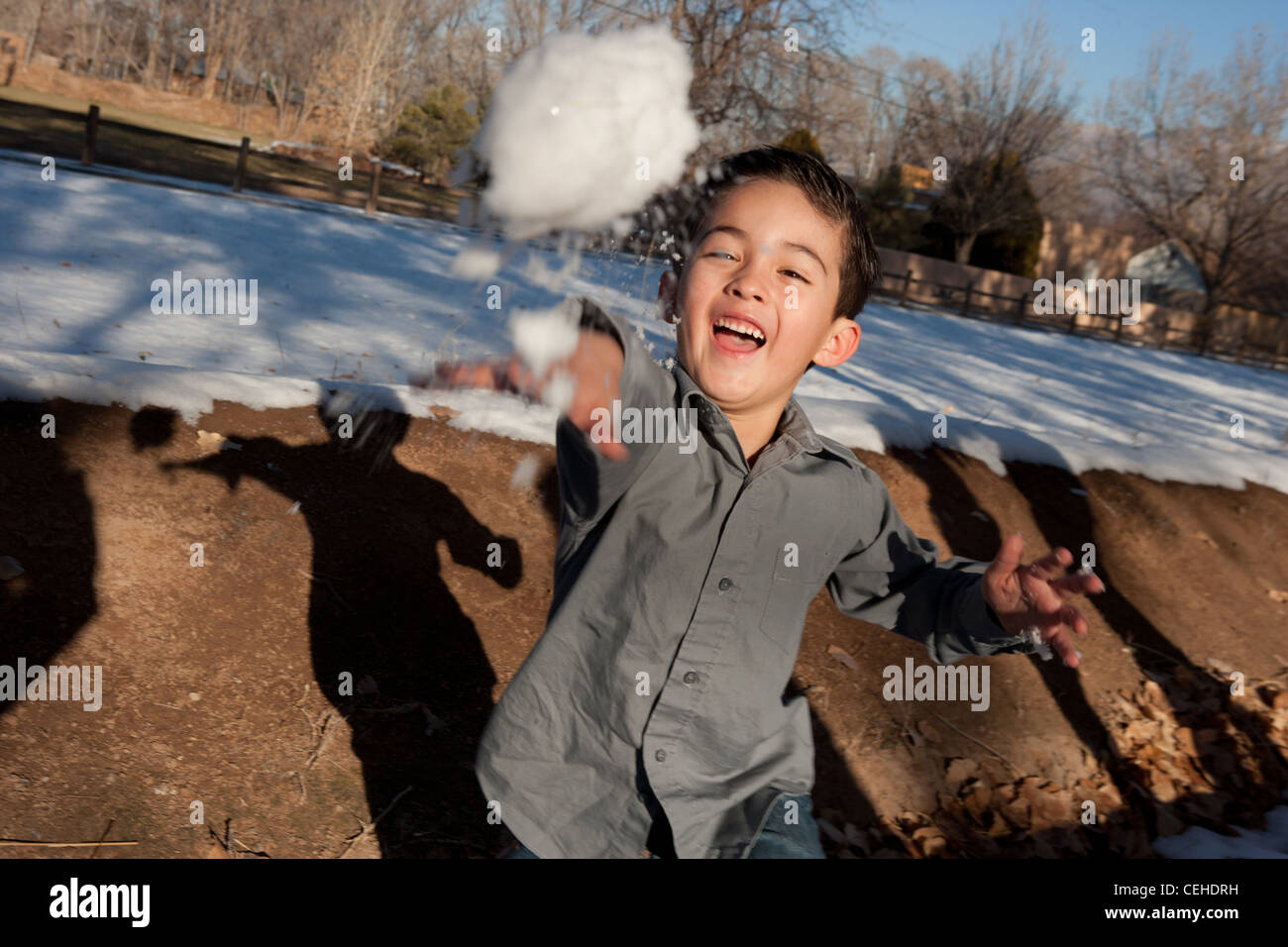 Seven year old Hispanic boy throwing a snowball at the camera with ...