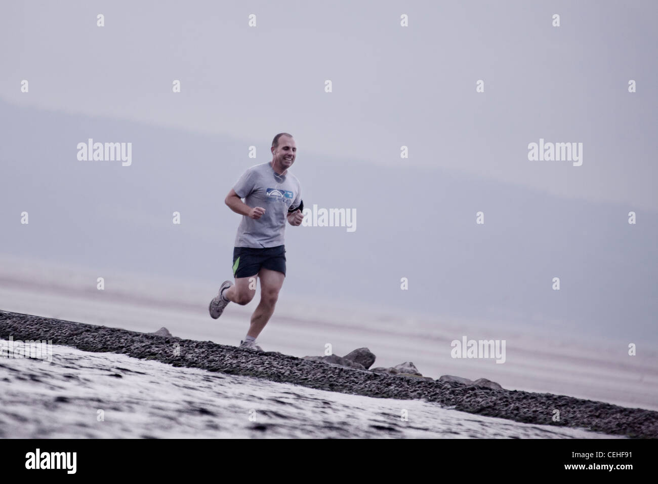 a man jogging around the perimeter of a marine lake at dusk Stock Photo ...