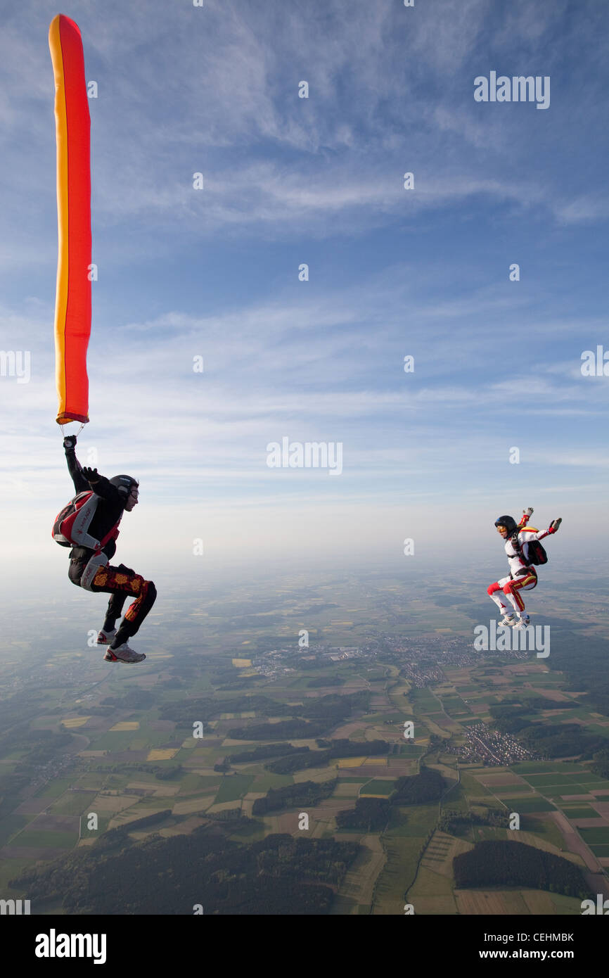 Skydiver with colorful air tube and friend are falling through the blue ...