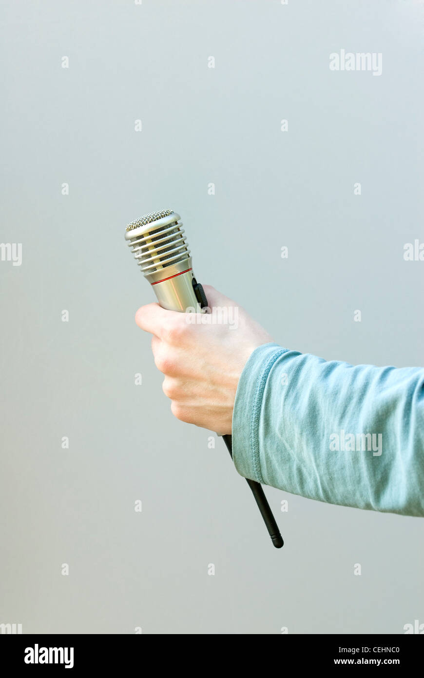 Hand holding radio microphone on gray background Stock Photo - Alamy