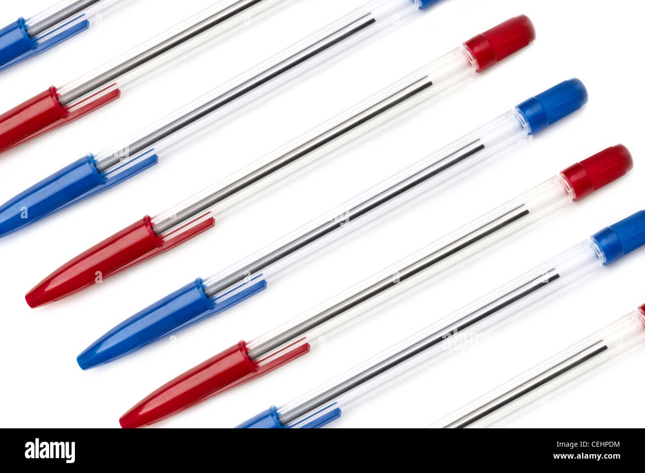 Close up capturing an arrangement of assorted biro pens over white ...