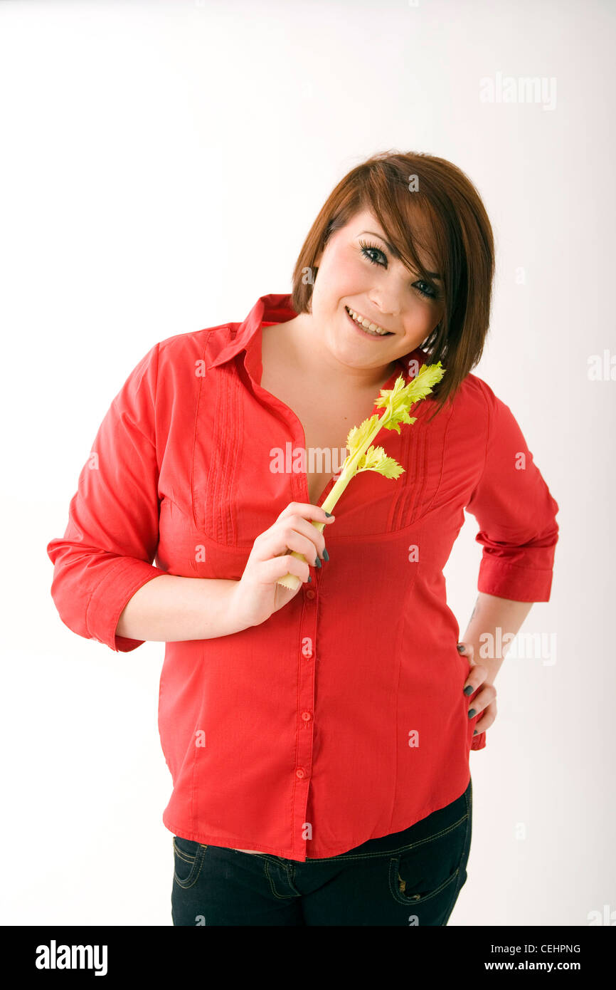 Slightly overweight woman standing holding a stick of celery Stock ...