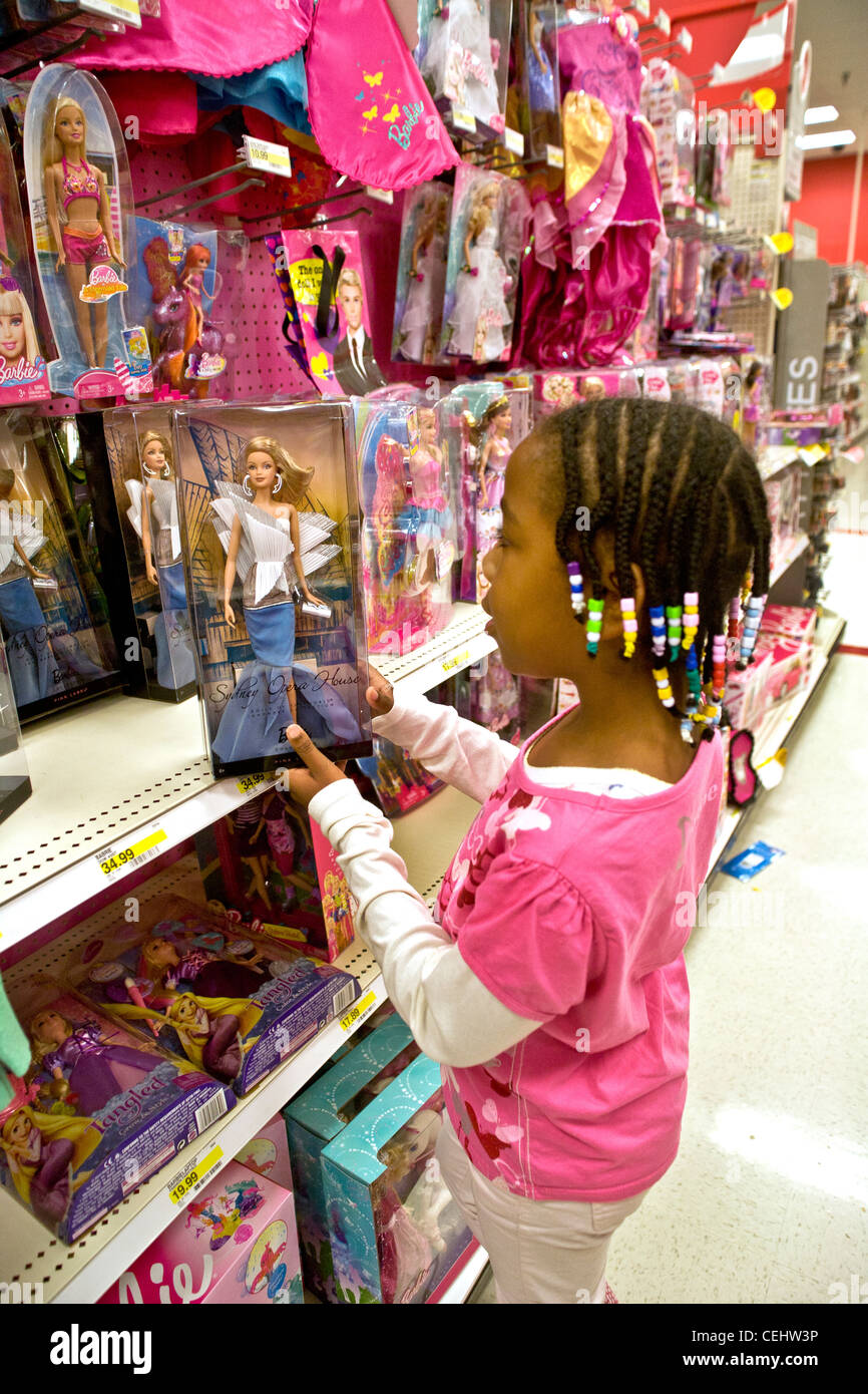 An African American 7-year-old girl shops for dolls at a discount store ...