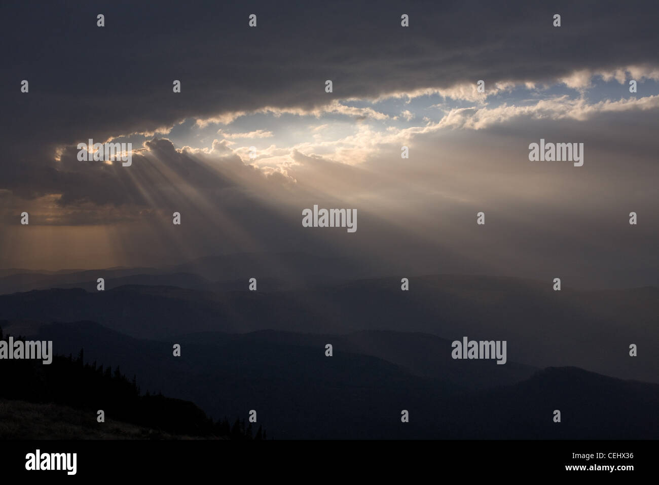 Rays of sun going through clouds, illuminating mountainous landscape ...