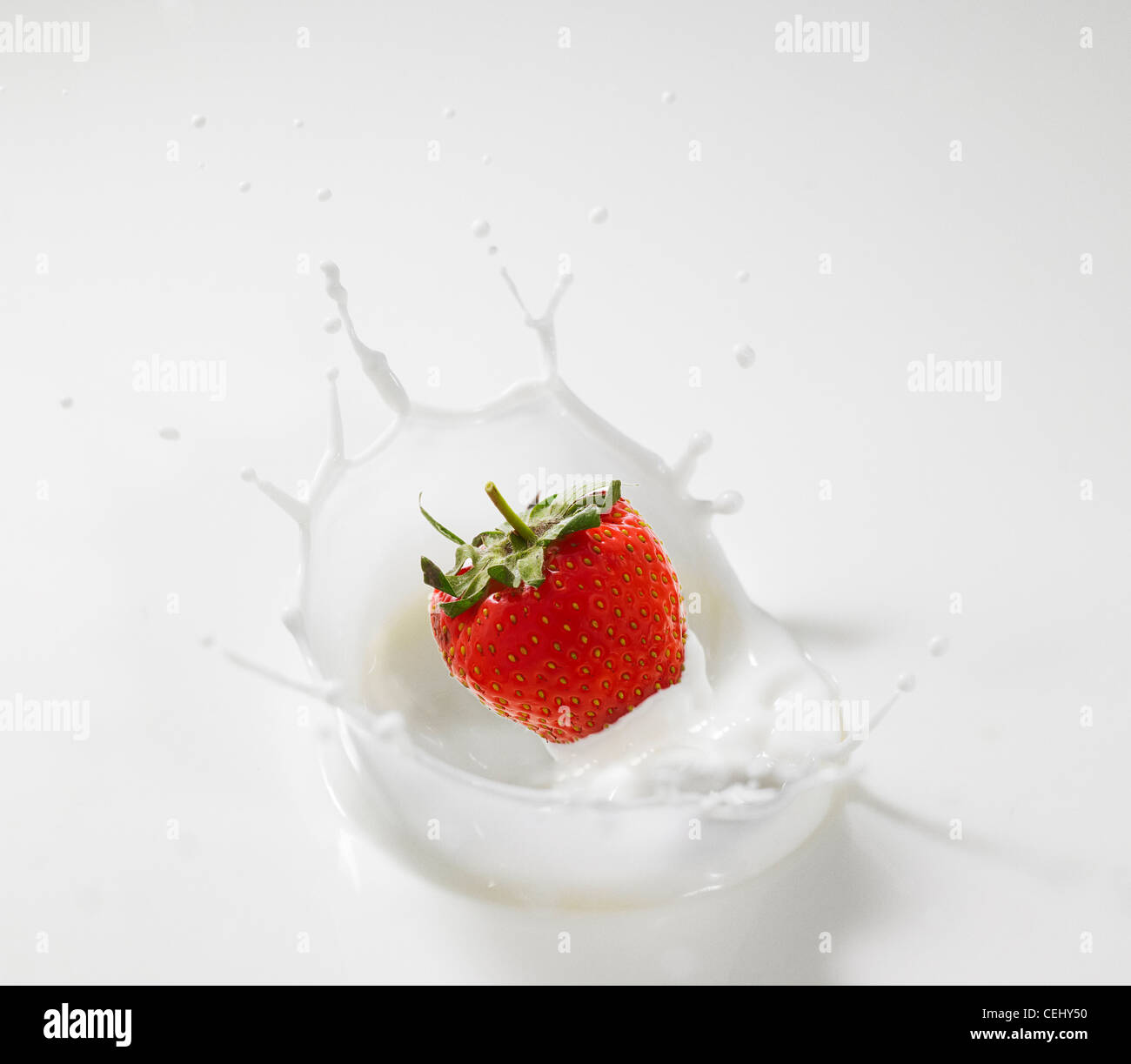 Strawberry dropped into milk with splash Stock Photo - Alamy