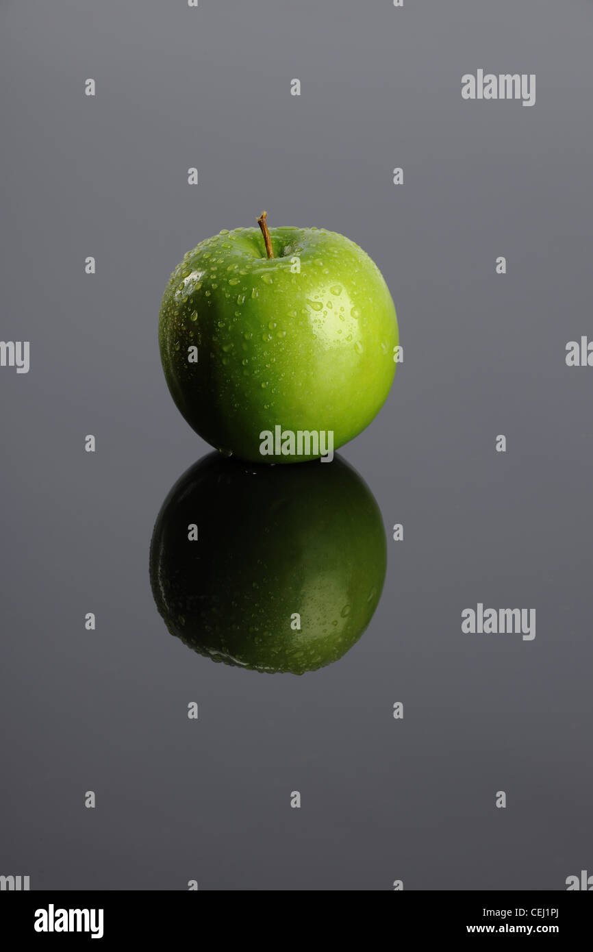 Green apple with reflection on a gray background Stock Photo - Alamy