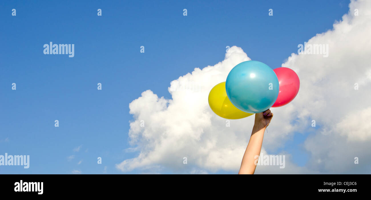 girls hand holding three colorful balloons and cloudy sky Stock Photo ...