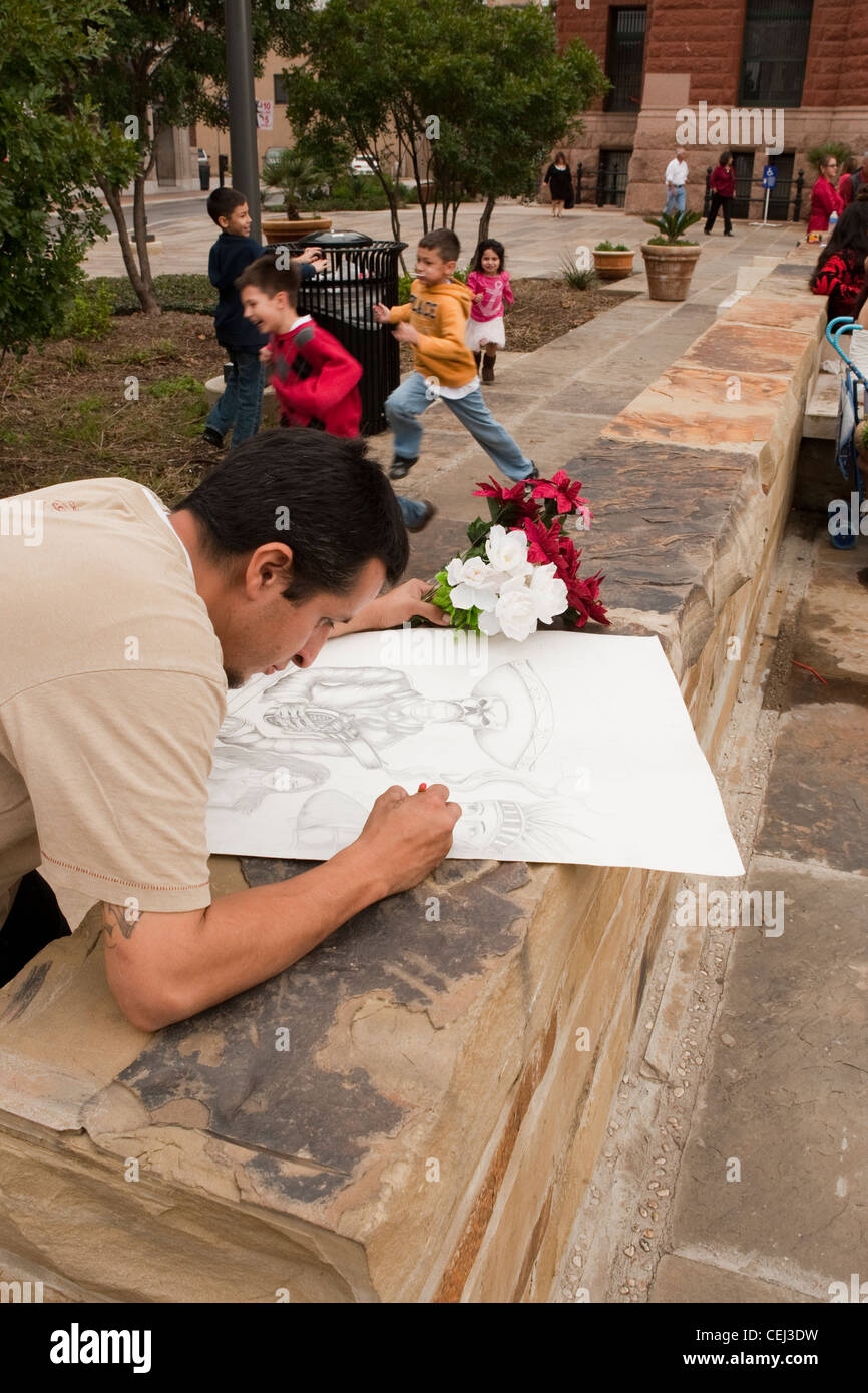 Young Hispanic male artist works on pencil drawing at an outdoor plaza ...