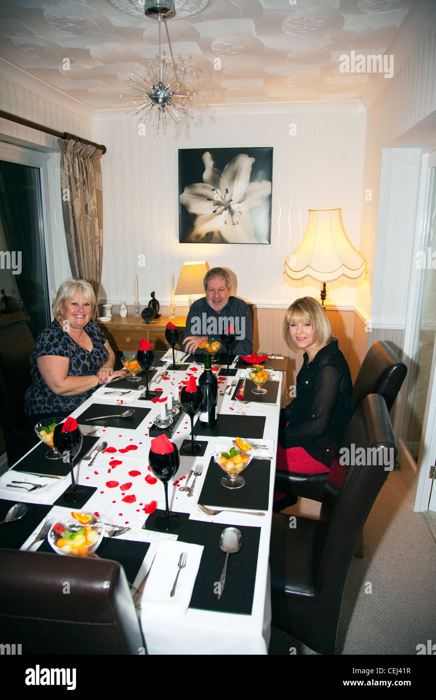 Three people sat at dinner table waiting for food to be served at home ...