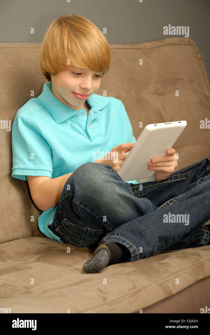 Eleven year old boy using tablet computer or e-reader while sitting on ...