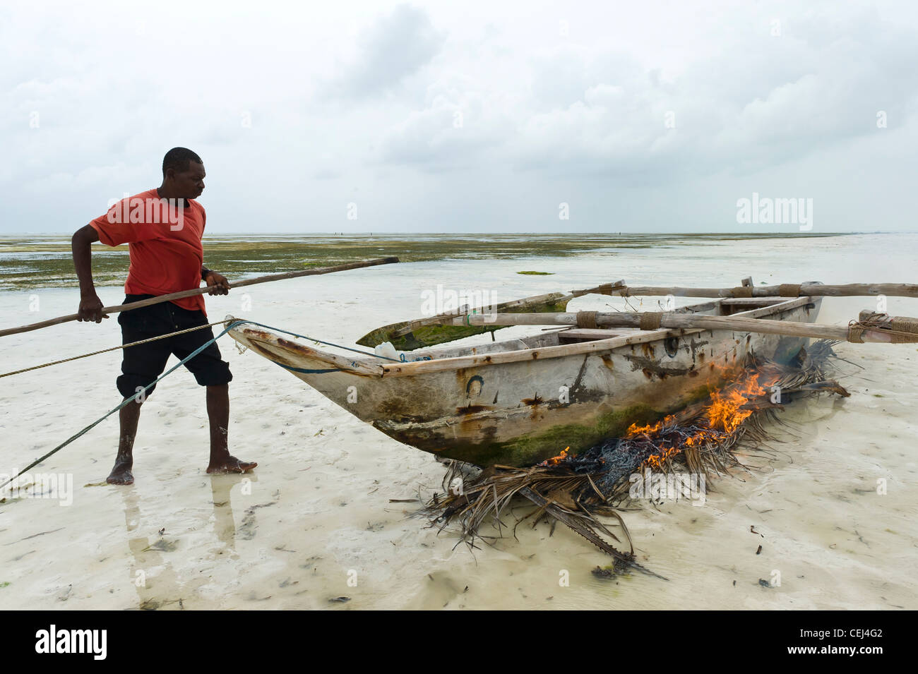 A fisherman burning algae and hardening his boat in Bwejuu Zanzibar ...