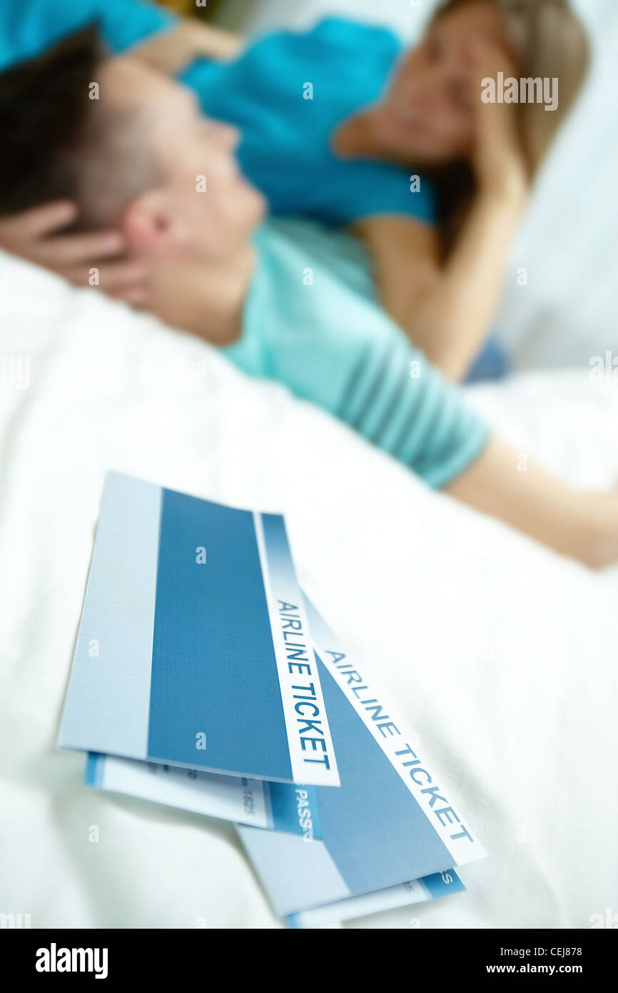 Image of airline tickets with happy young couple lying on bed Stock ...