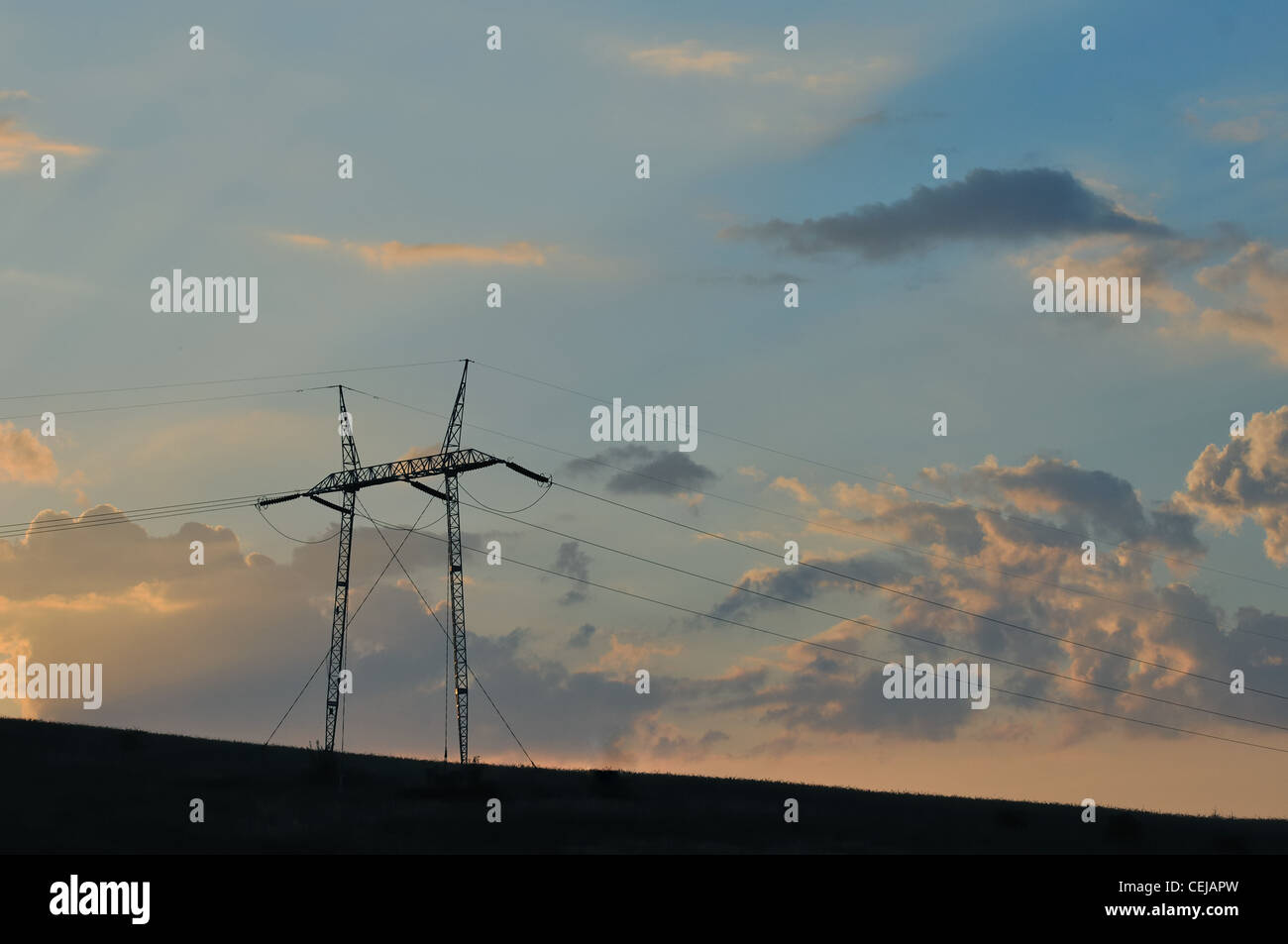Sunset with high voltage electric pylon in field Stock Photo - Alamy