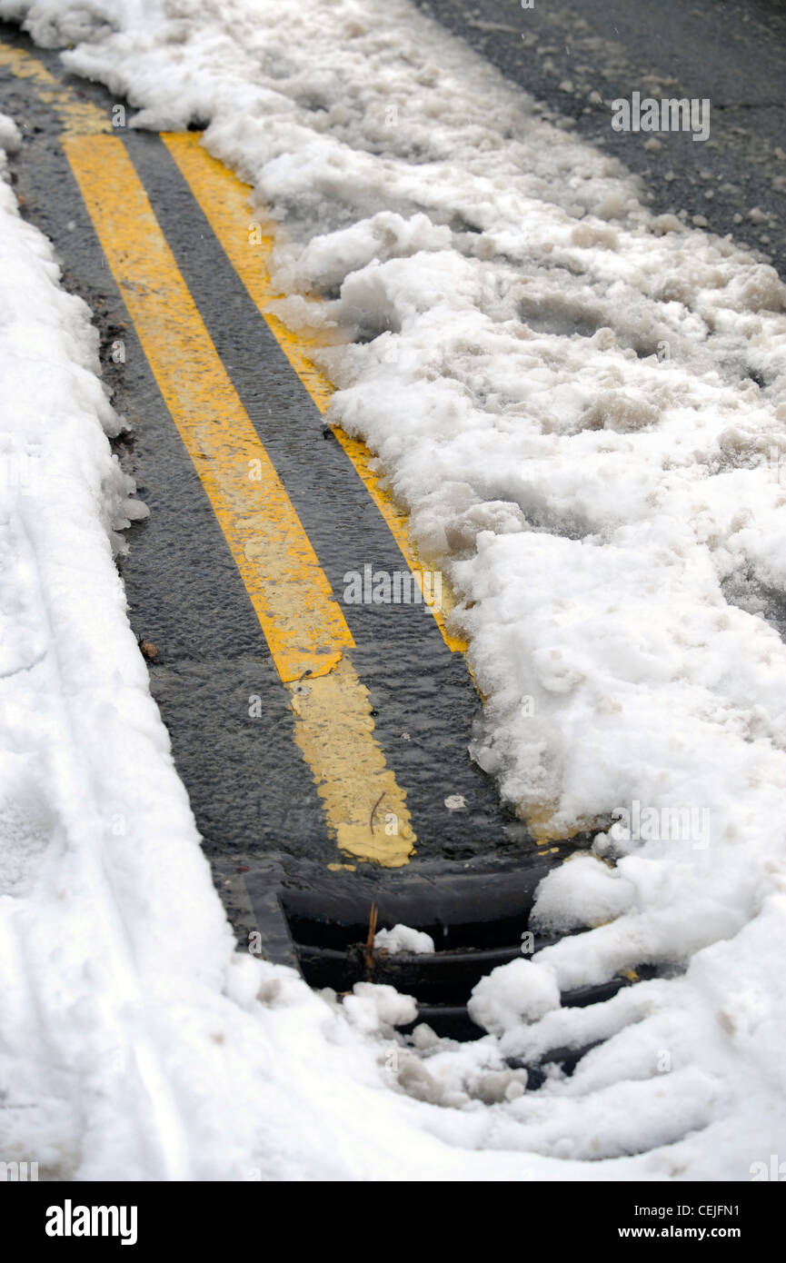 A double yellow line road marking emerges from under thawing snow UK ...