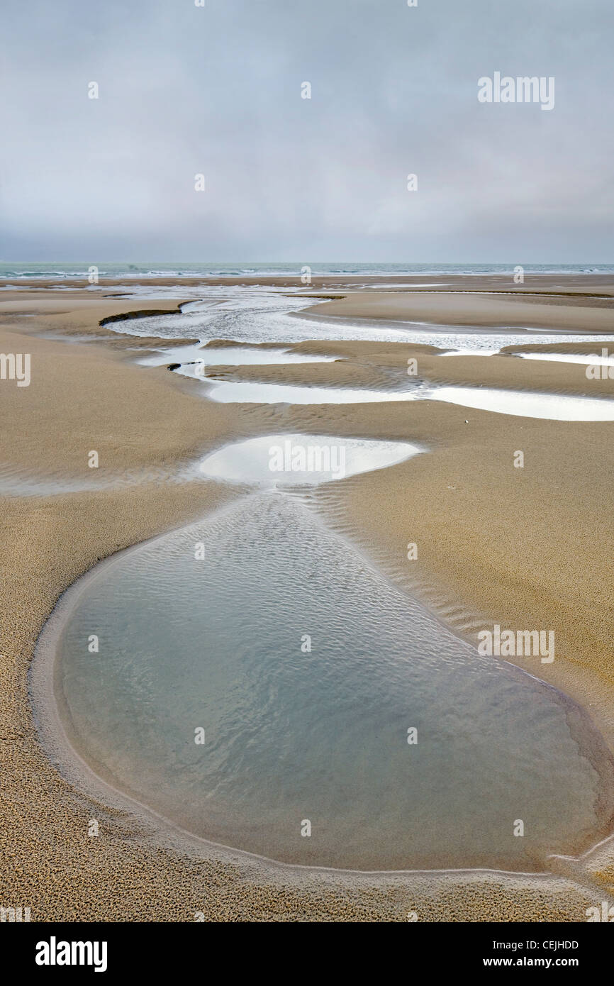 Tide pools on sand beach at low tide and rain clouds over Cap Blanc Nez ...