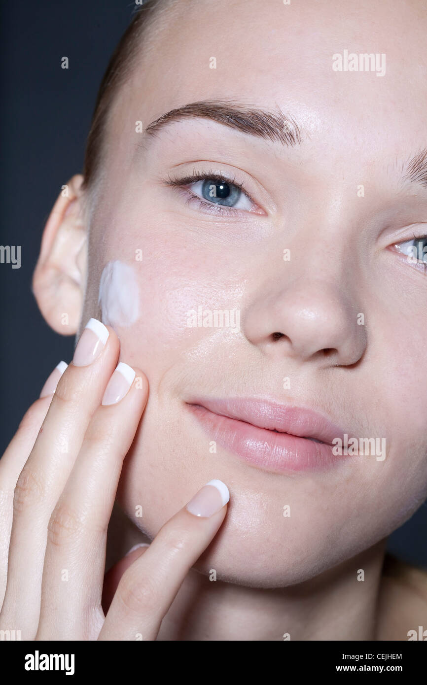 Step by Step Beauty and Make Up Female applying face cream to her cheek ...
