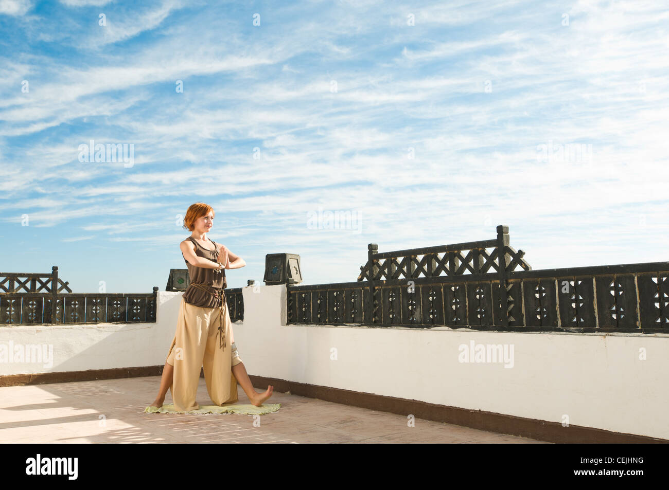 Beautiful young dancer performing yoga-dance outdoors with blue sky and ...