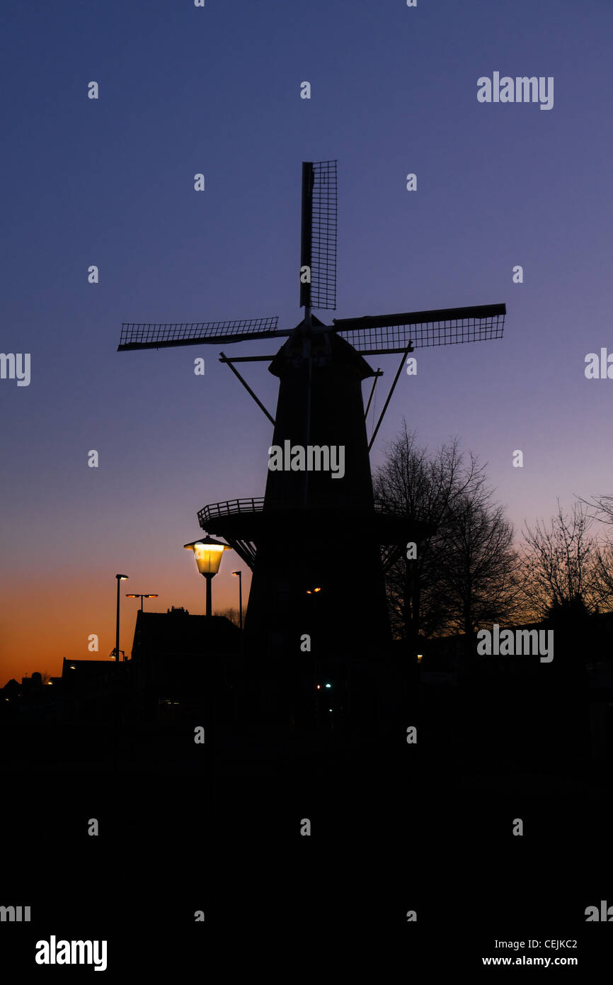 Silhouette of Dutch windmill in city with streetlights after sunset ...