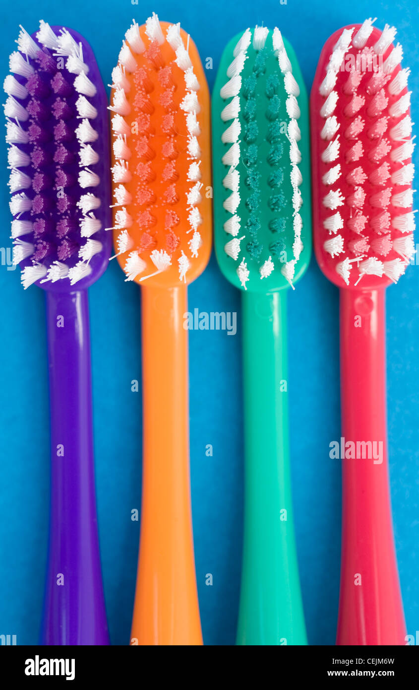 A close up of purple, yellow, green and red toothbrushes in a row on a ...