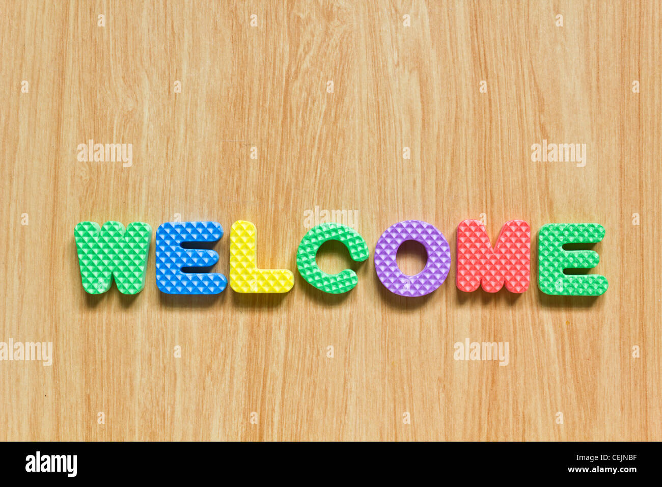 colorful letters with welcome isolated on wood texture Stock Photo - Alamy