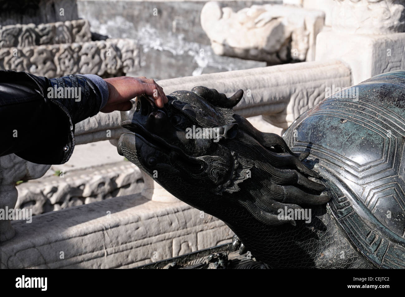man touching Bronze statue turtle dragons head outside Tai He Dian Hall ...