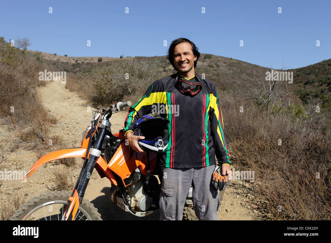 Man standing in front of motorcycle on dirt road Stock Photo - Alamy