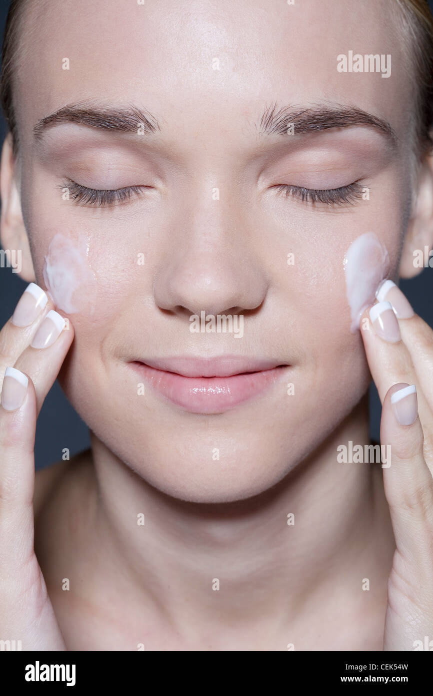 Step by Step Beauty and Make Up Female applying face cream to her cheek ...