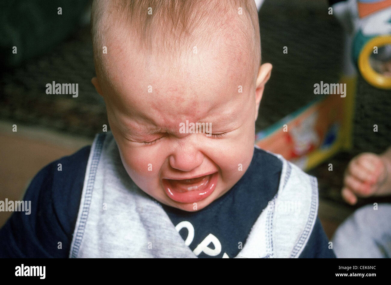 Baby crying eyes closed head down showing two lower front teeth wearing ...