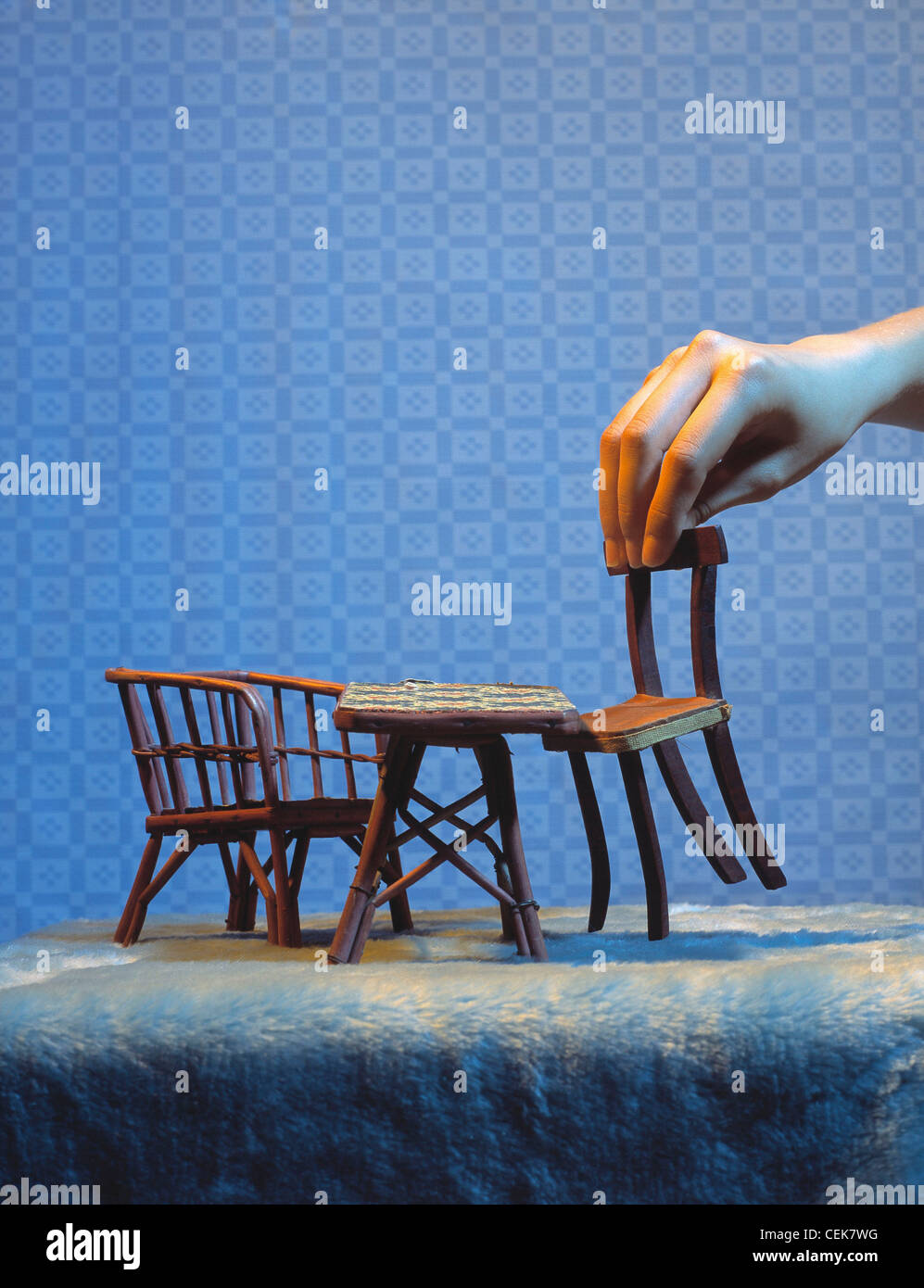 Female hand placing miniature toy wooden chair on furry surface ...