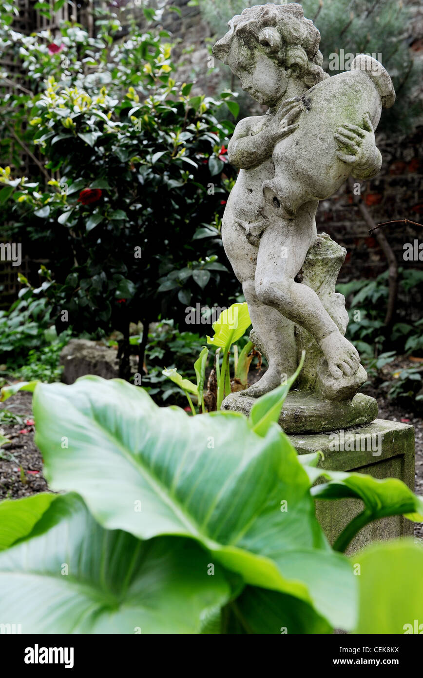 Hidden Treasure Stone sculpture of cherub with vase in the garden with ...